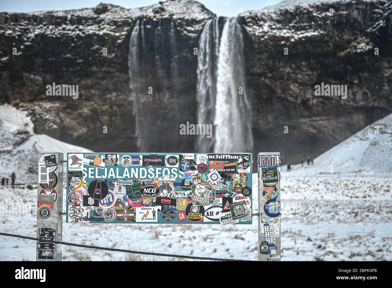 Sign covered with stickers reading “Seljalandsfoss” in front of ...