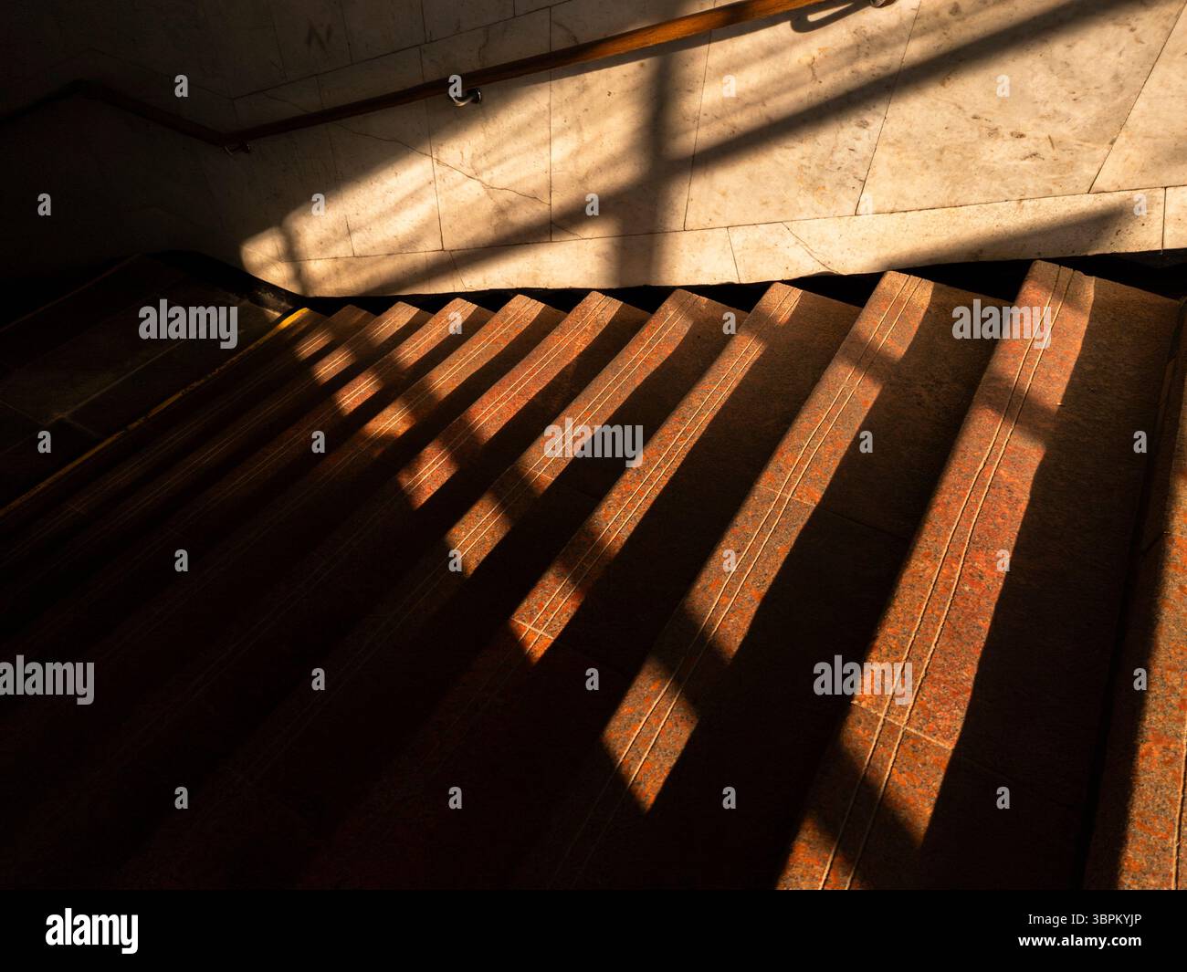 Warm sunlight creates intricate shadows on the textured stone steps of ...