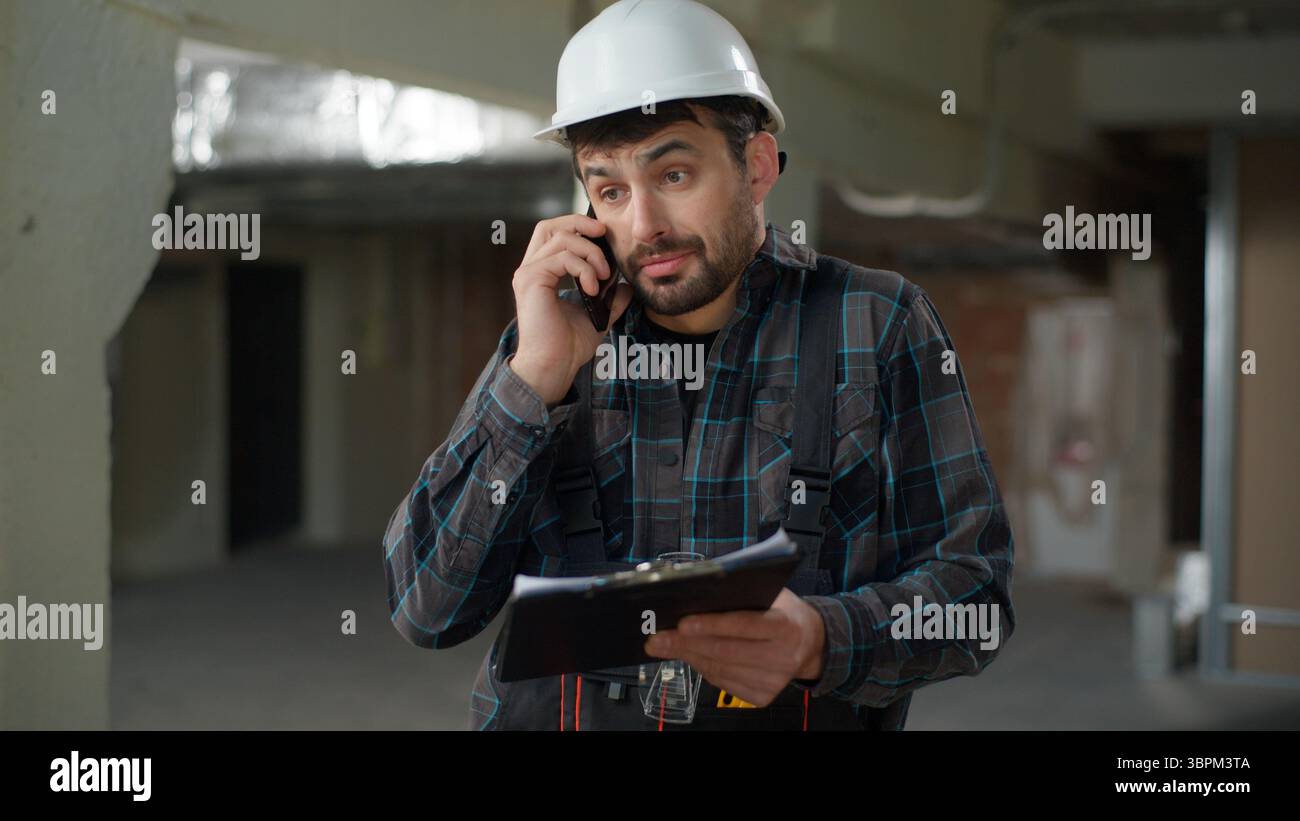 Caucasian man foreman builder talking mobile phone on construction site ...