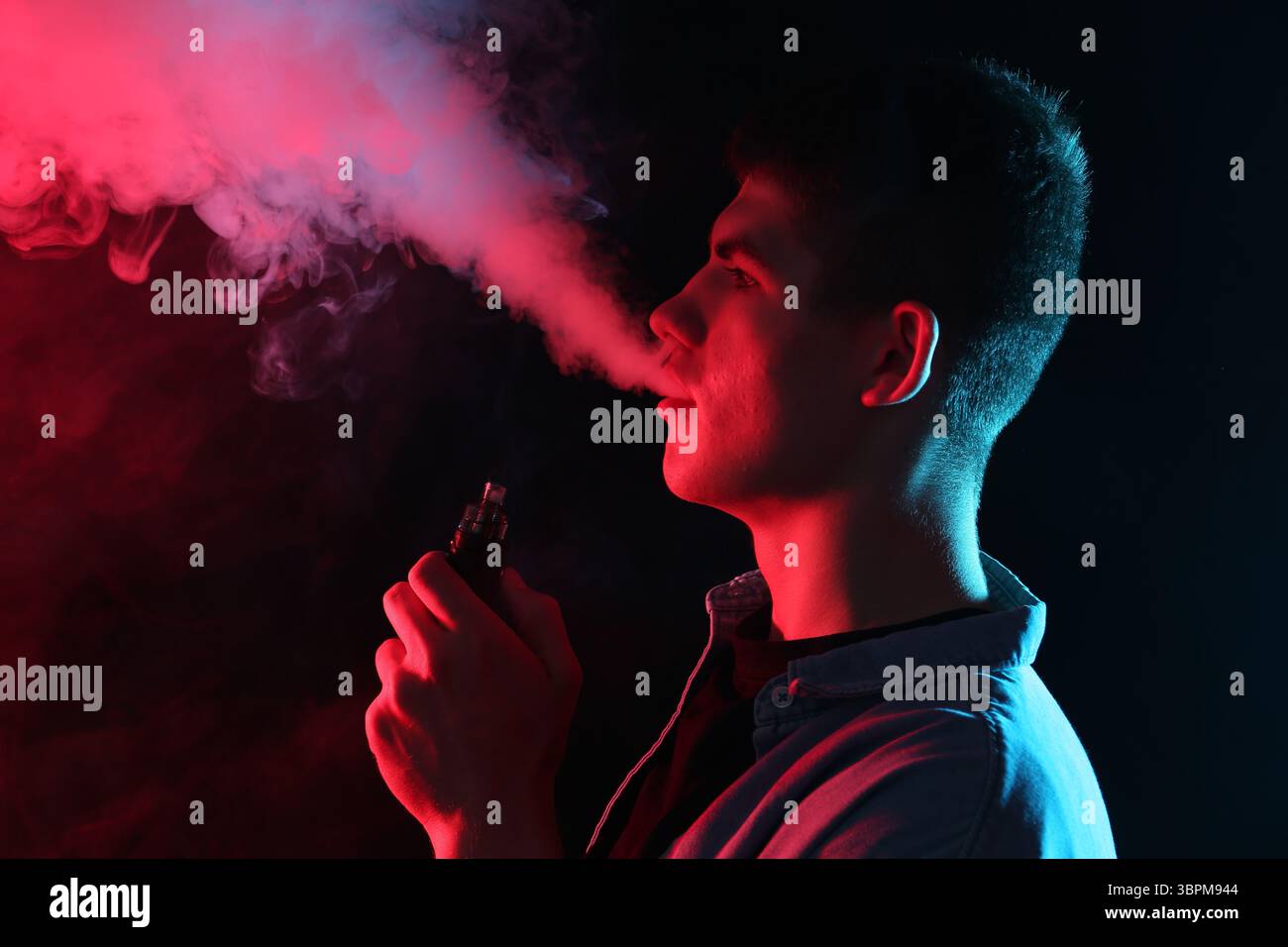 Man using electronic smoking device in neon lights on black background ...