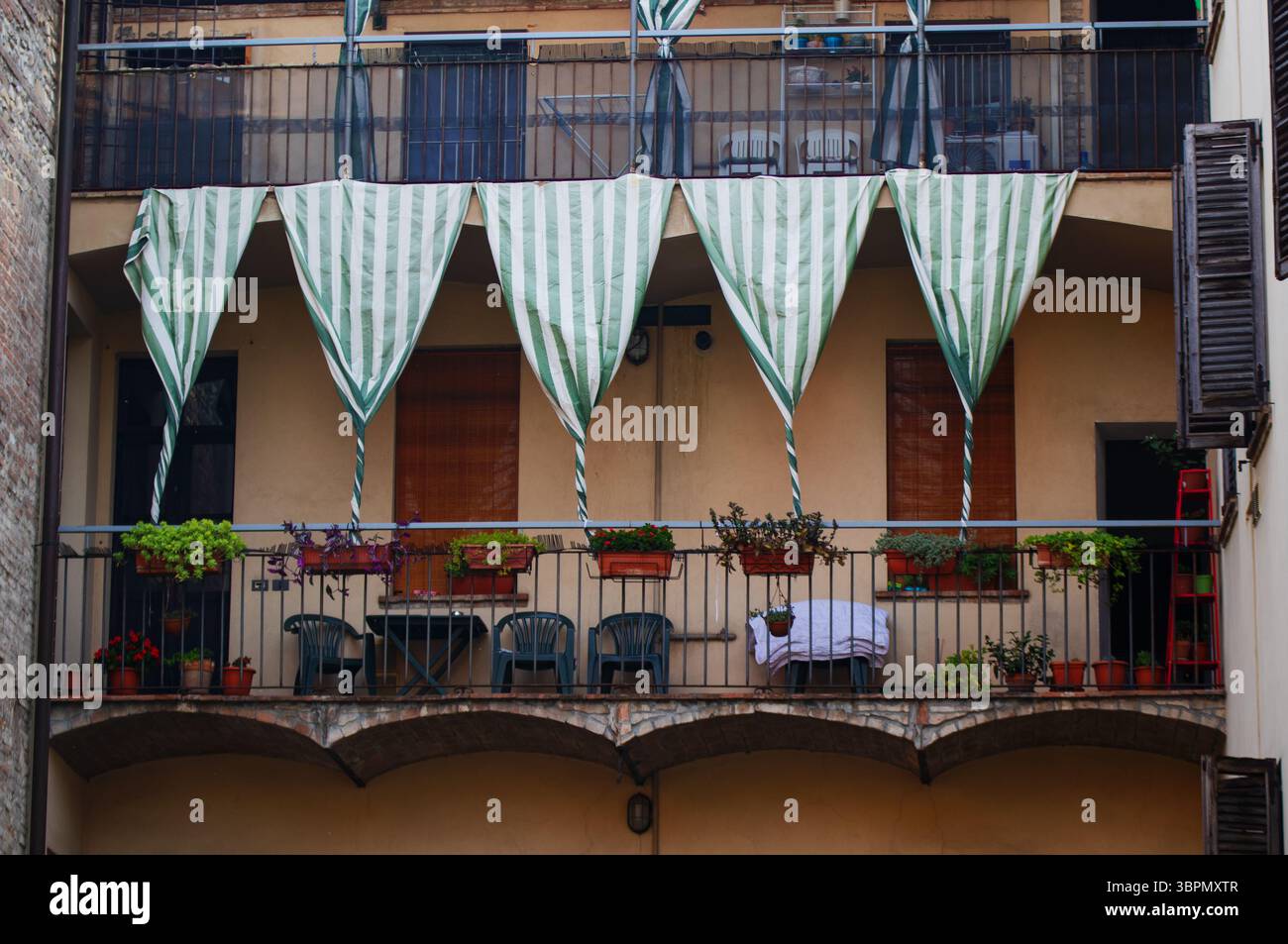 Picturesque Italian balcony green striped awnings potted plants ...