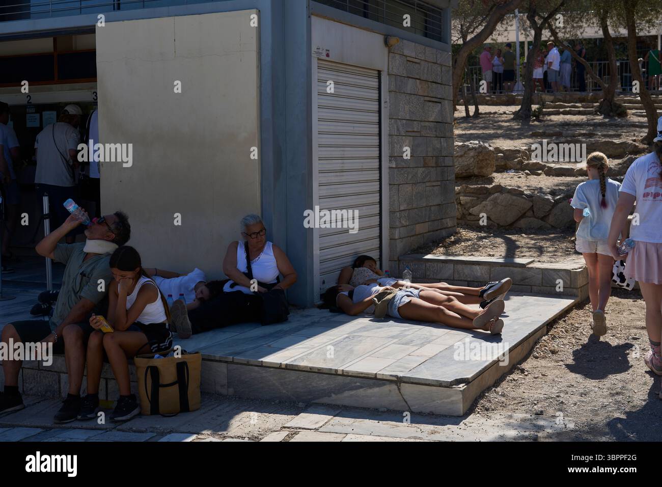 A tourist drinks water as others sleep outside the entrance of the ...