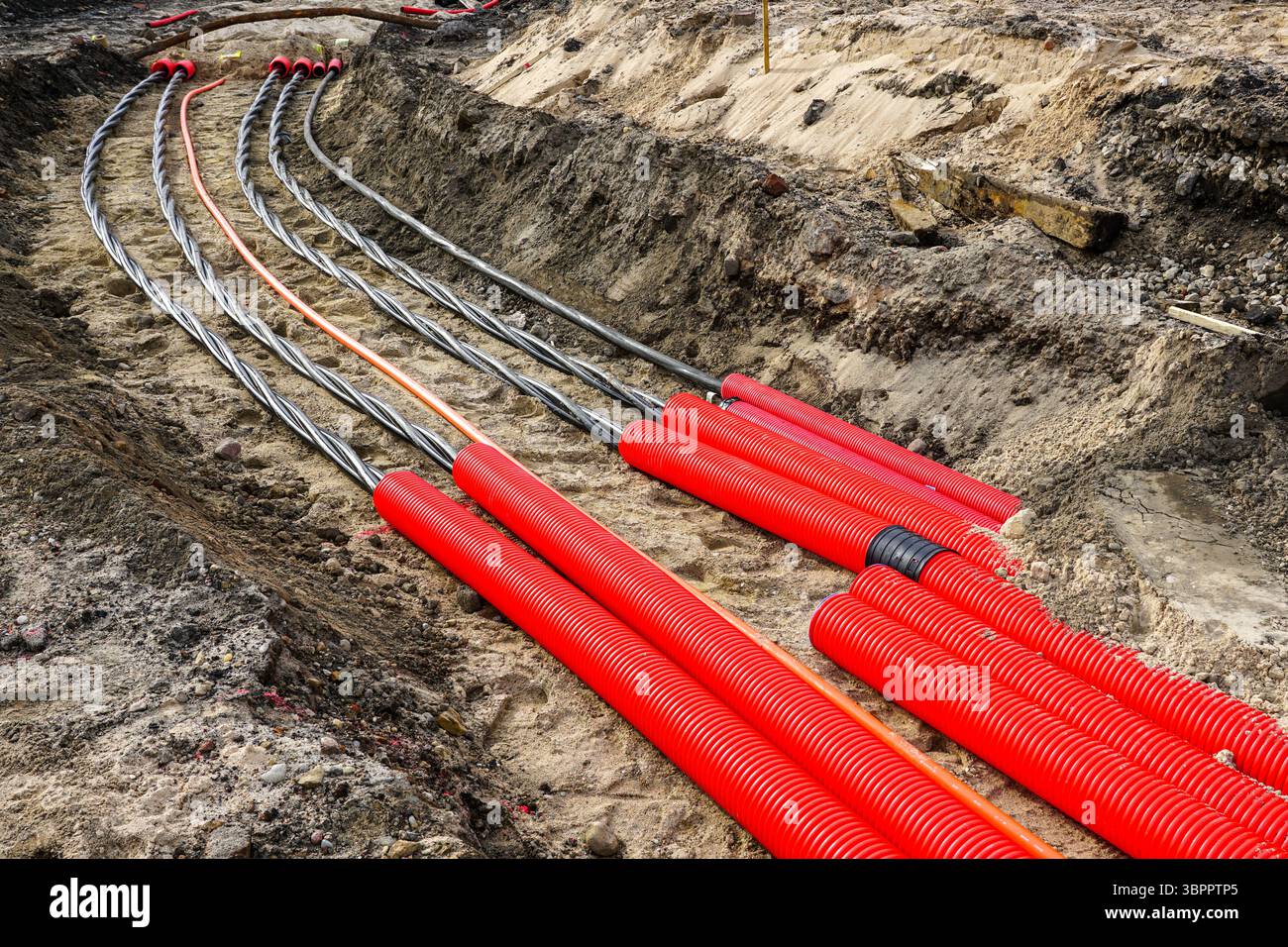 Underground electrical cable installation with red conduits laid in a ...