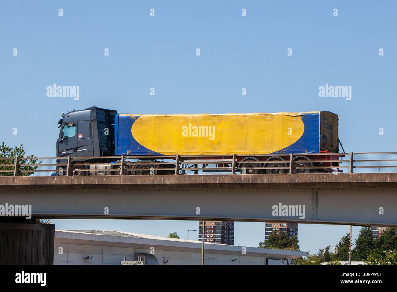 A dark blue articulated lorry with a blue and yellow curtain-sided ...