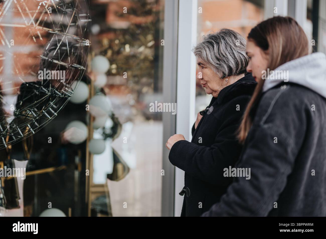 Elderly woman and younger companion observing a window display outdoors ...