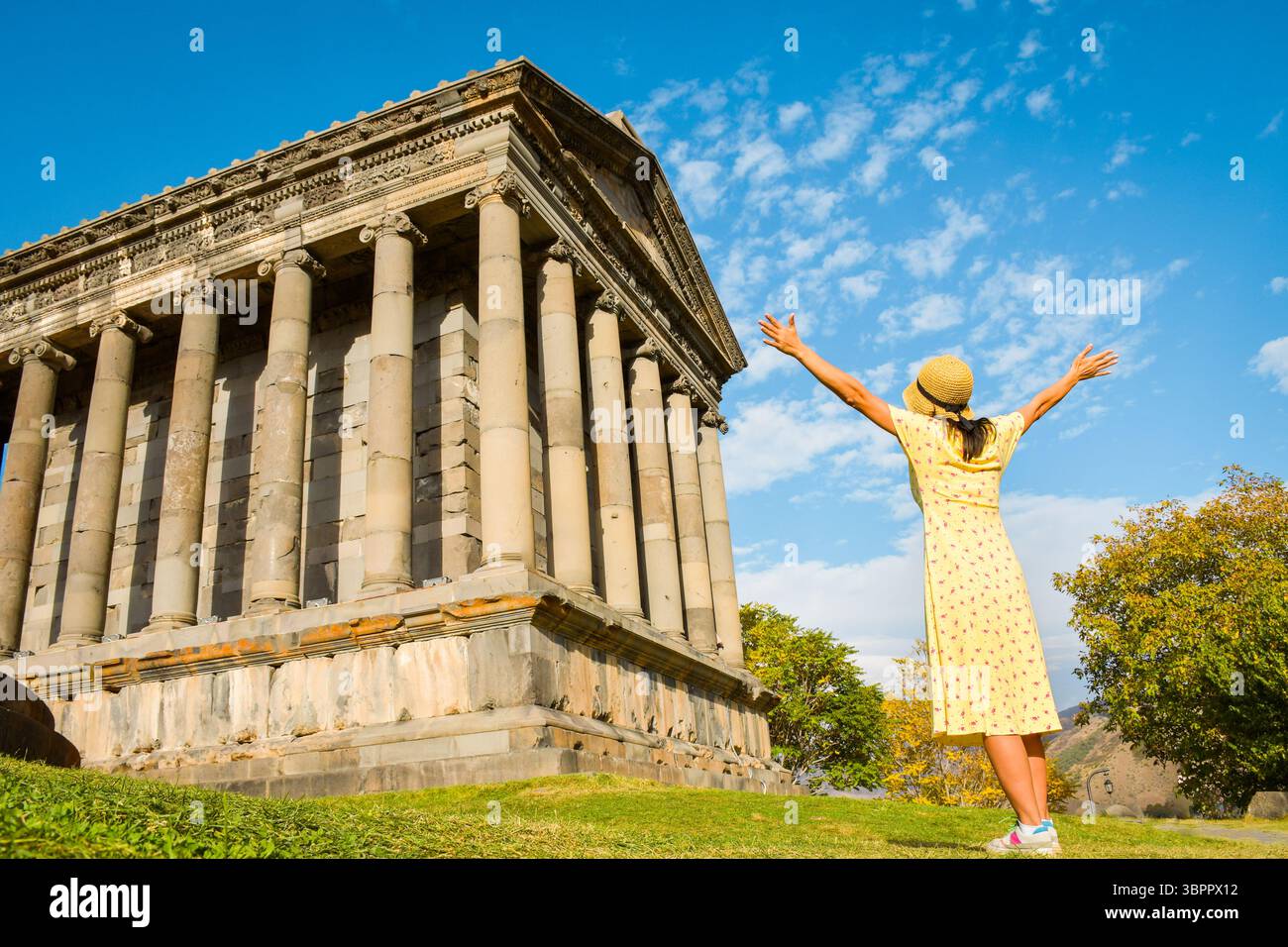 Happy tourist blogger arms up by famous roman The Garni Temple ...