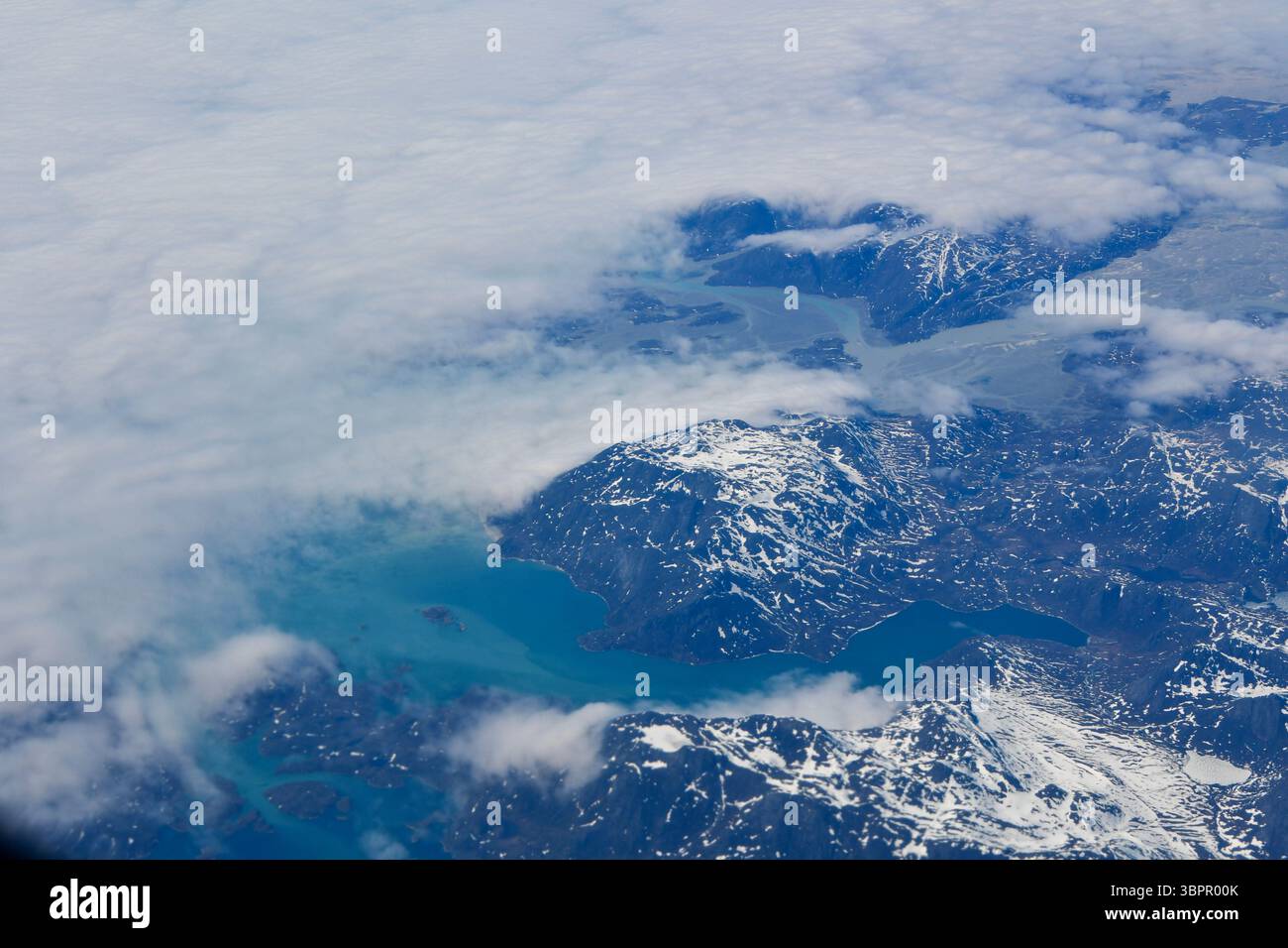 Aerial view of a coastal fjord and mountains in Greenland, partially ...