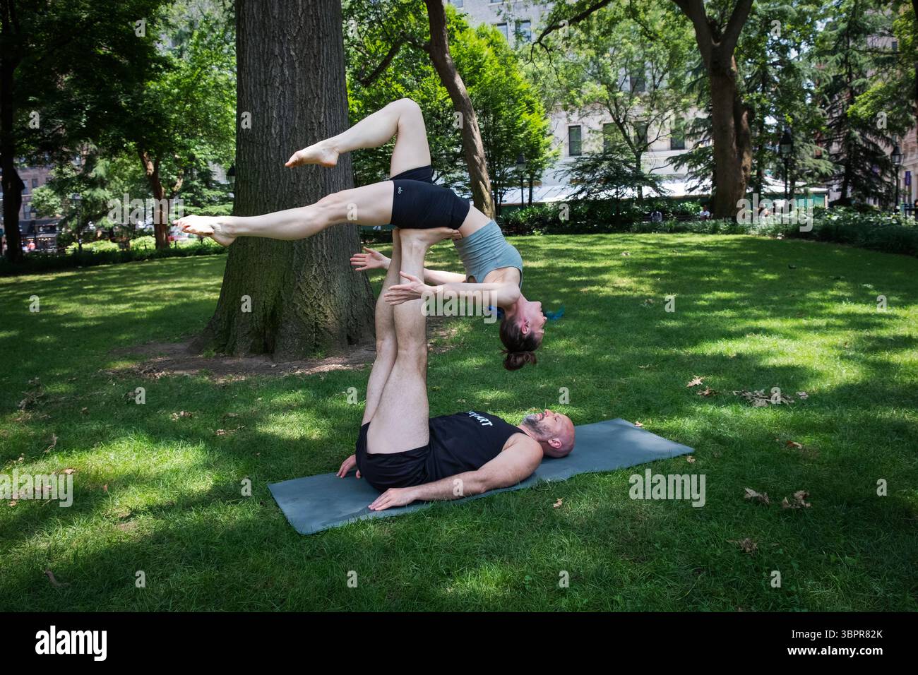 A graceful attractive lady performs Acroyoga, a practice that combines ...