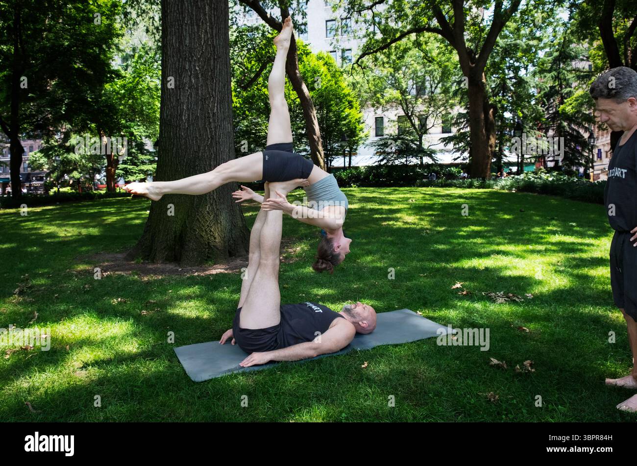 A graceful attractive lady performs Acroyoga, a practice that combines ...