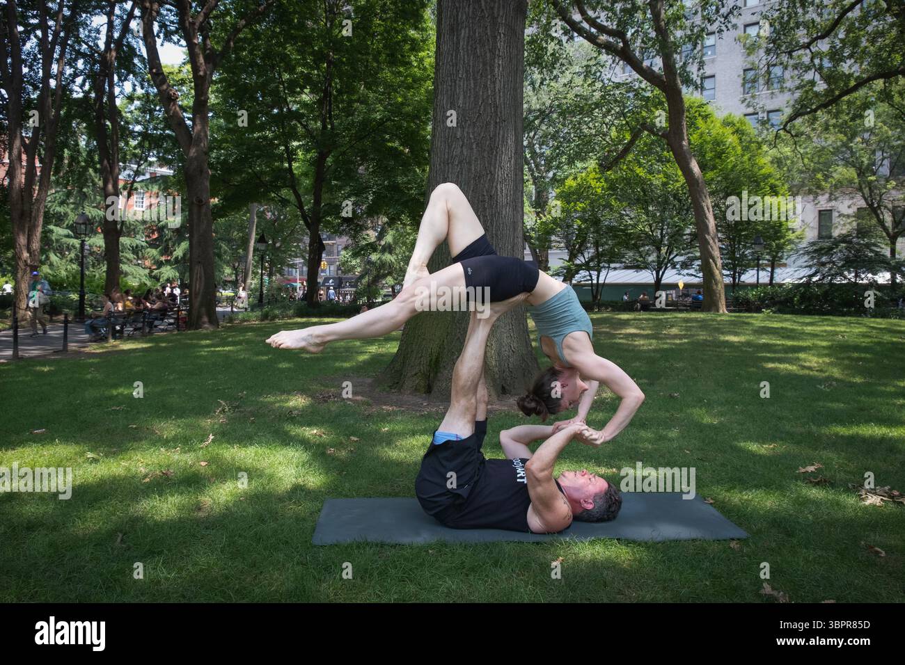 A graceful attractive lady performs Acroyoga, a practice that combines ...