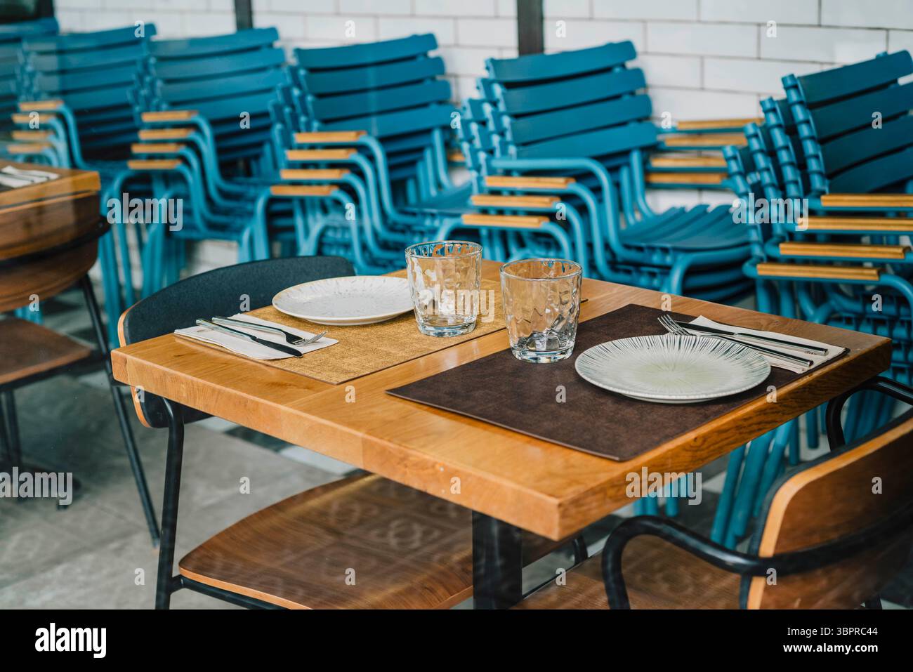 Empty restaurant table setup with stacked blue chairs Stock Photo - Alamy