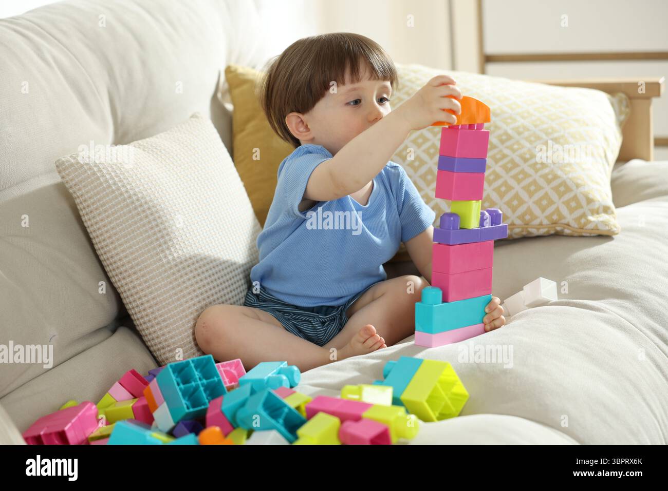 Cute little child playing with building bricks on sofa at home Stock ...