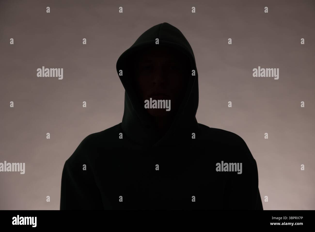 Silhouette of anonymous man in hood on grey background Stock Photo - Alamy