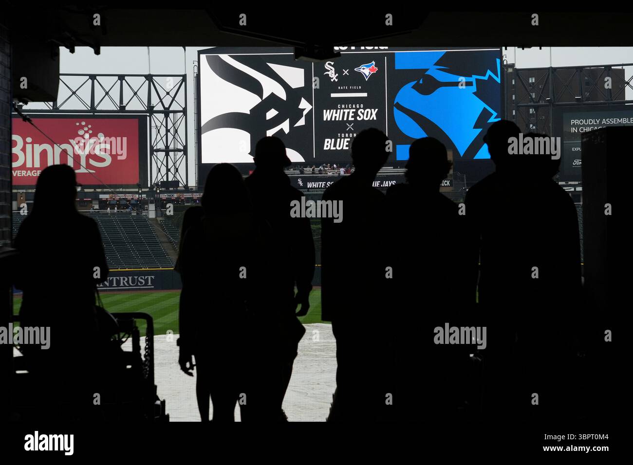 A tarp covers the infield and fans look to the field as they wait for a ...