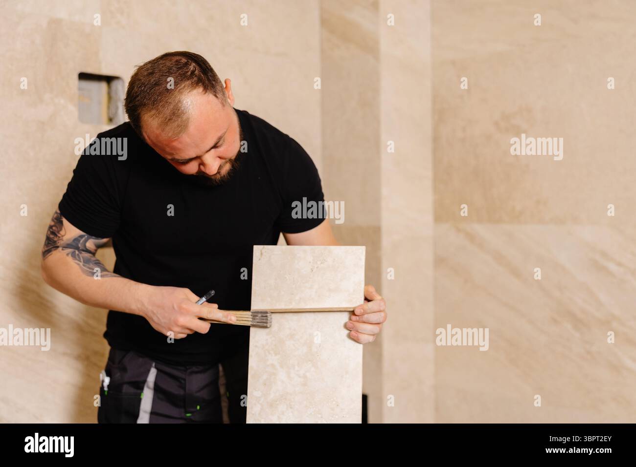 Professional tiler placing large format travertine tiles on bathroom ...