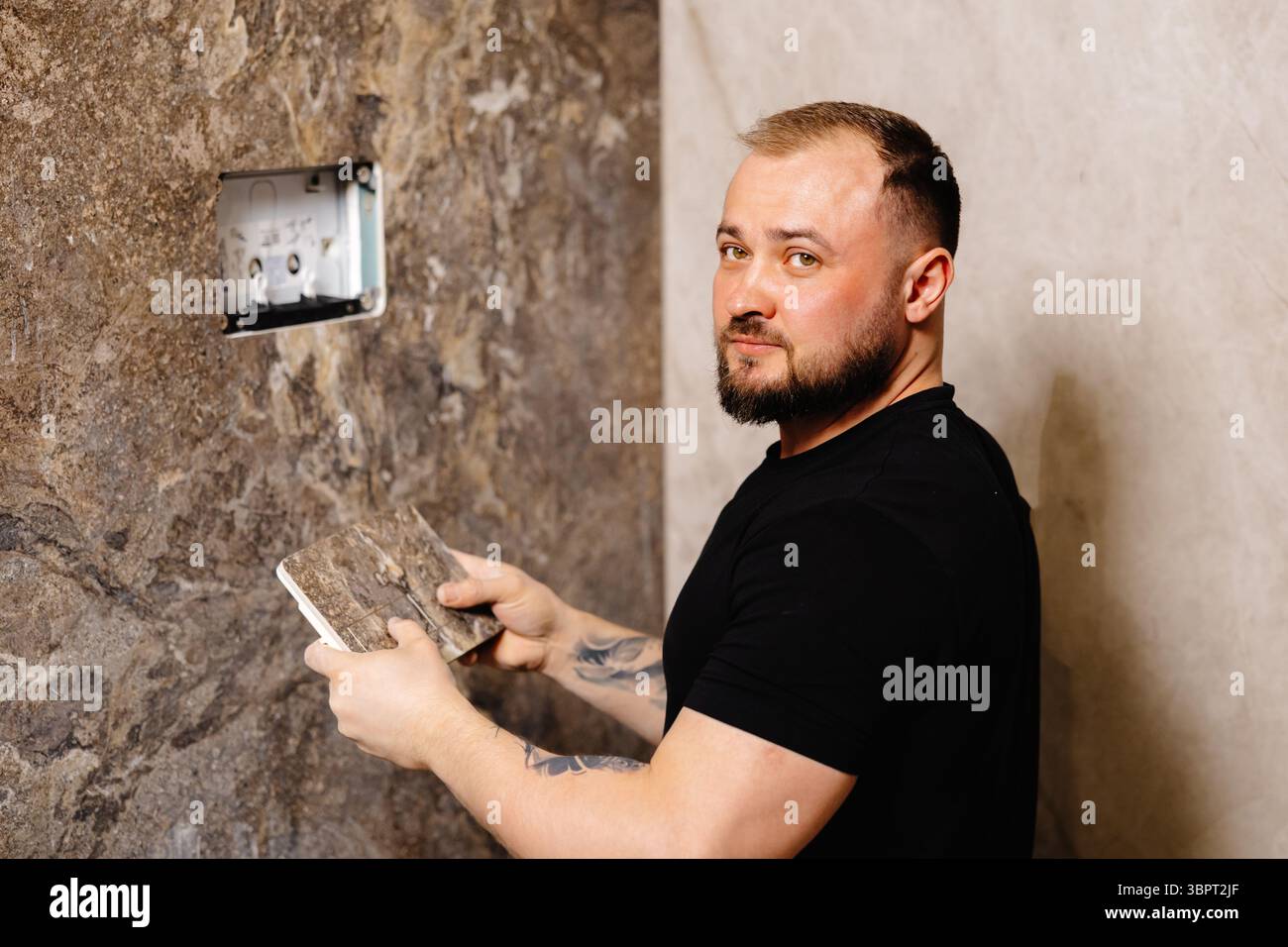Builder placing ceramic tiles on a wall, skillfully transforming a bathroom during renovation ...