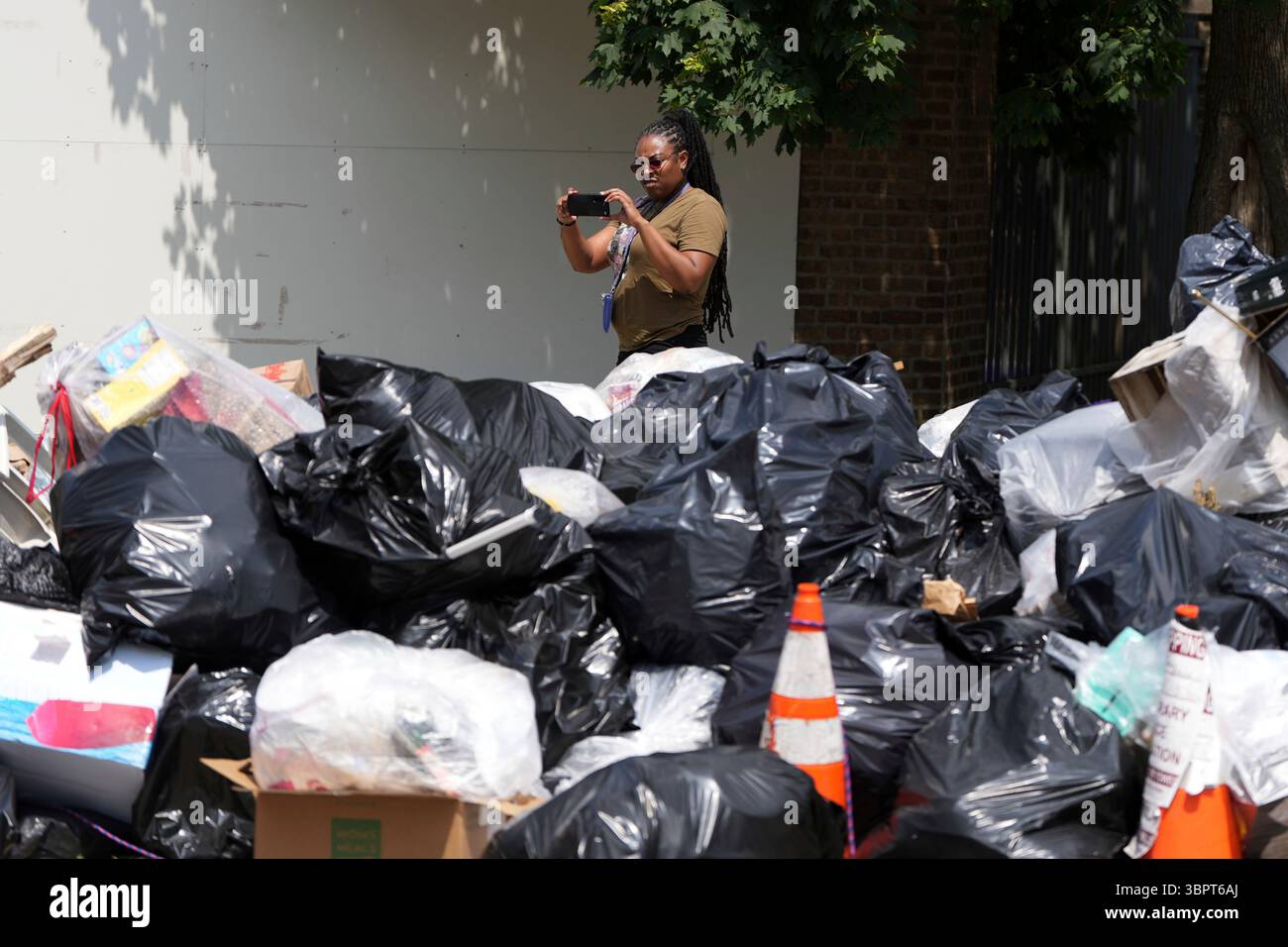A woman records a garbage collection site, Wednesday, July 9, 2025, in ...