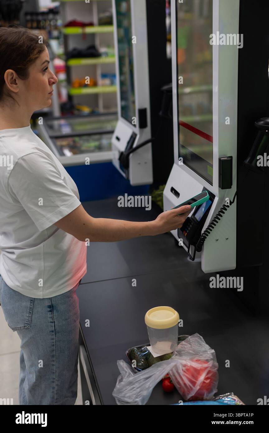 A woman pays using her smartphone at a self-checkout Stock Photo - Alamy