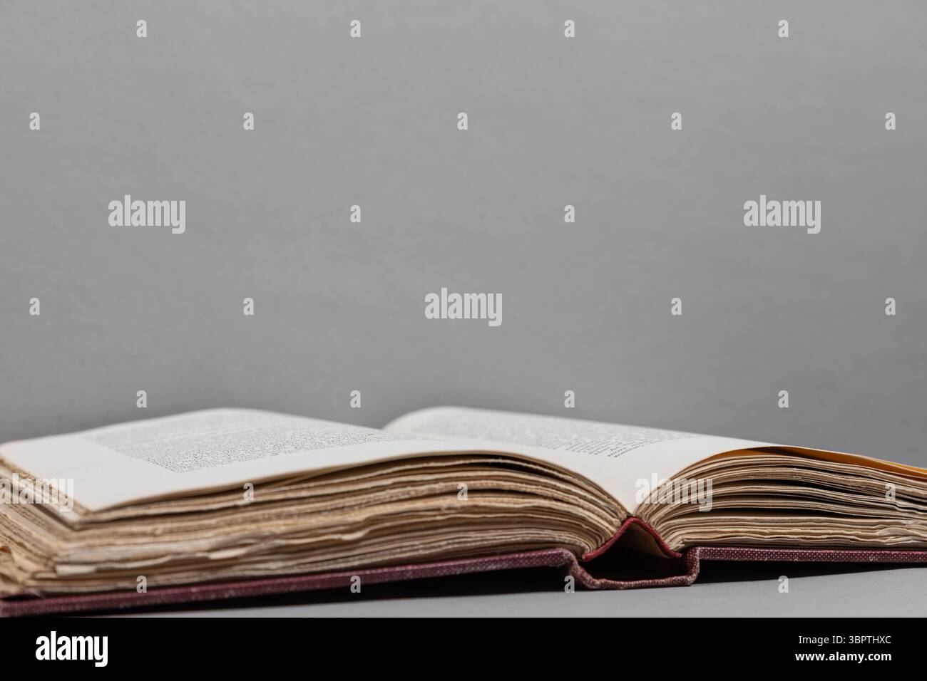 Open antique book with uneven deckled page edges on dark textured ...