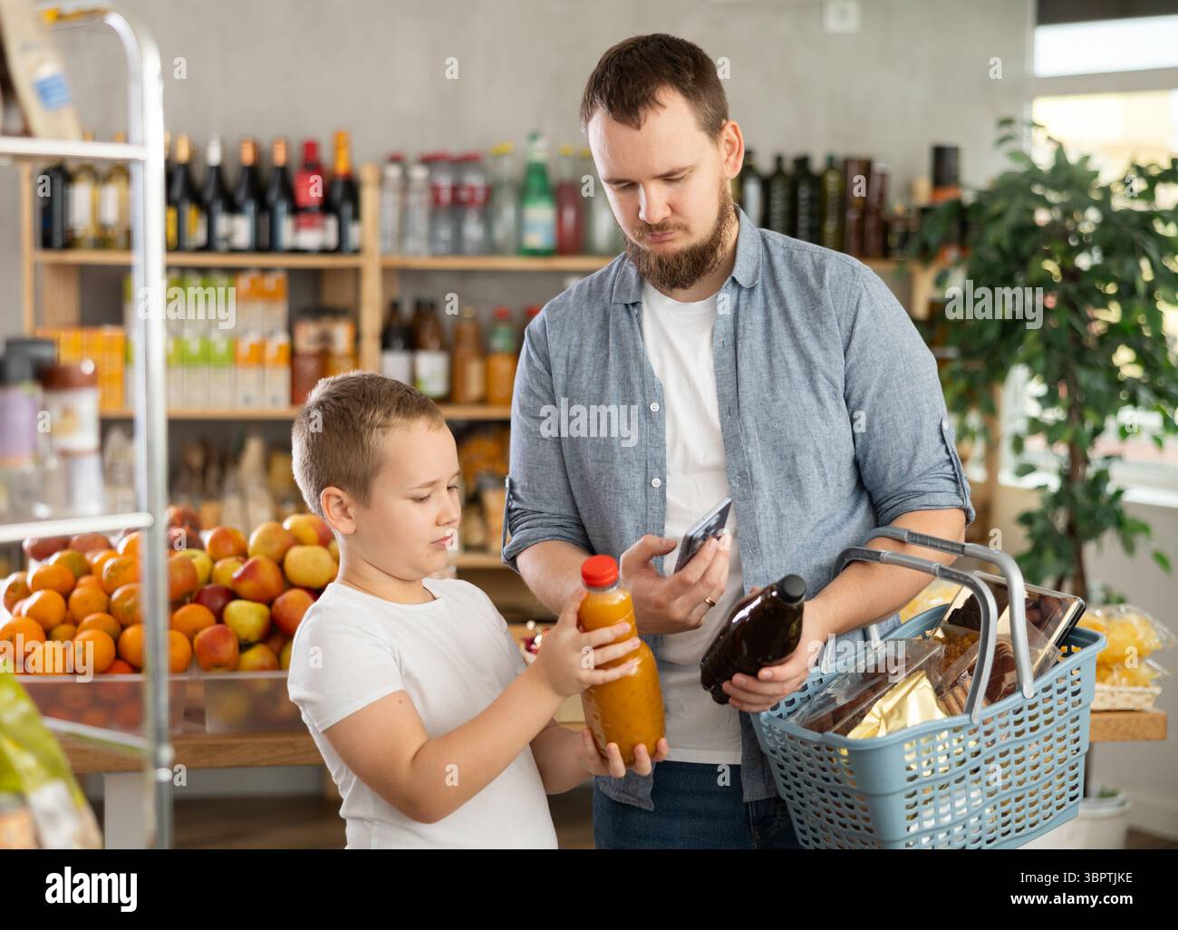 European man with son customer at shop scans QR code on juice bottle ...