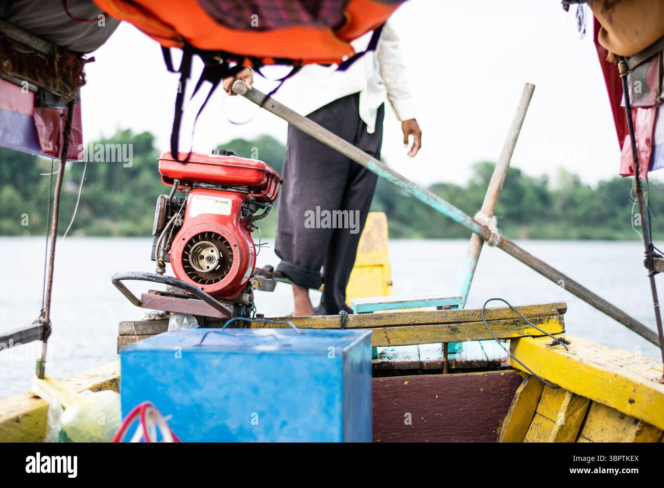 Boatman maneuvering traditional wooden boat with outboard motor on ...