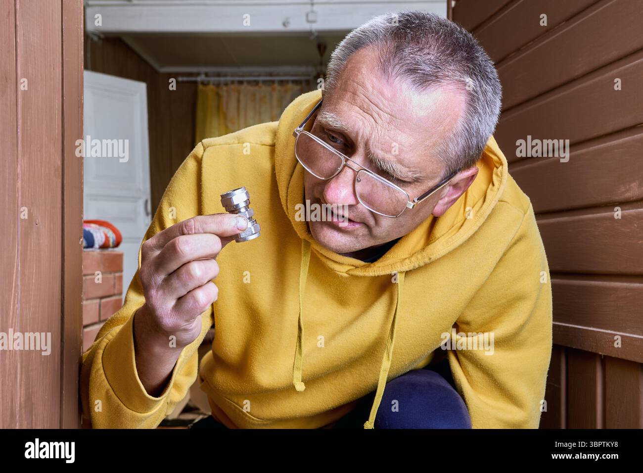 Repairman examines compression fitting for multilayer pipe held in hand ...