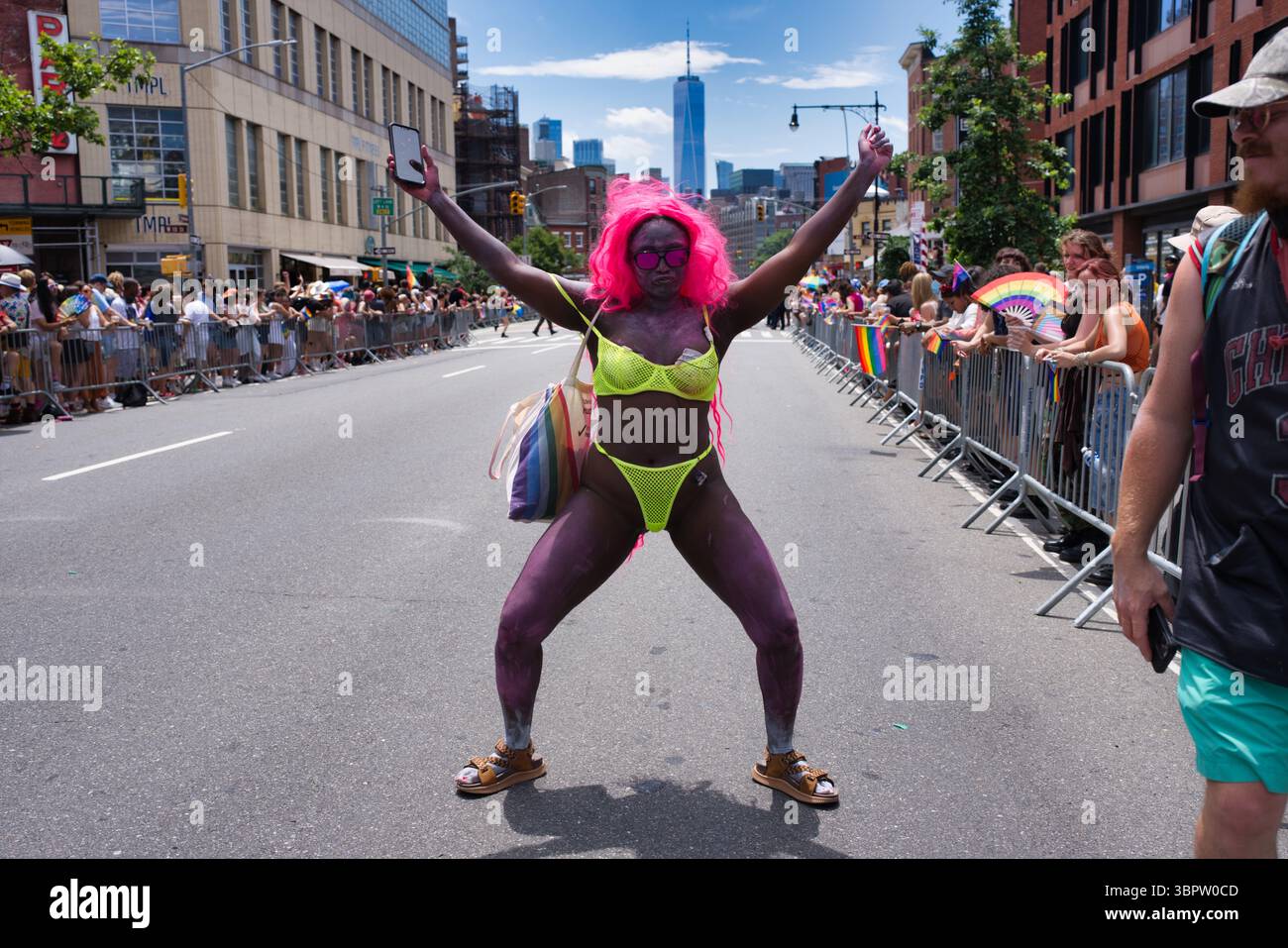 A person with pink hair and purple body paint wears a neon yellow ...