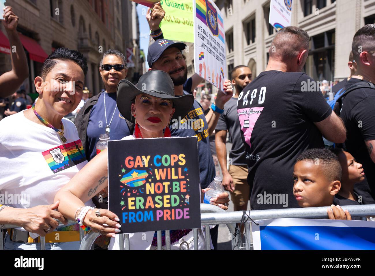 A diverse group of people at a Pride parade, holding signs advocating for LGBTQ+ rights ...