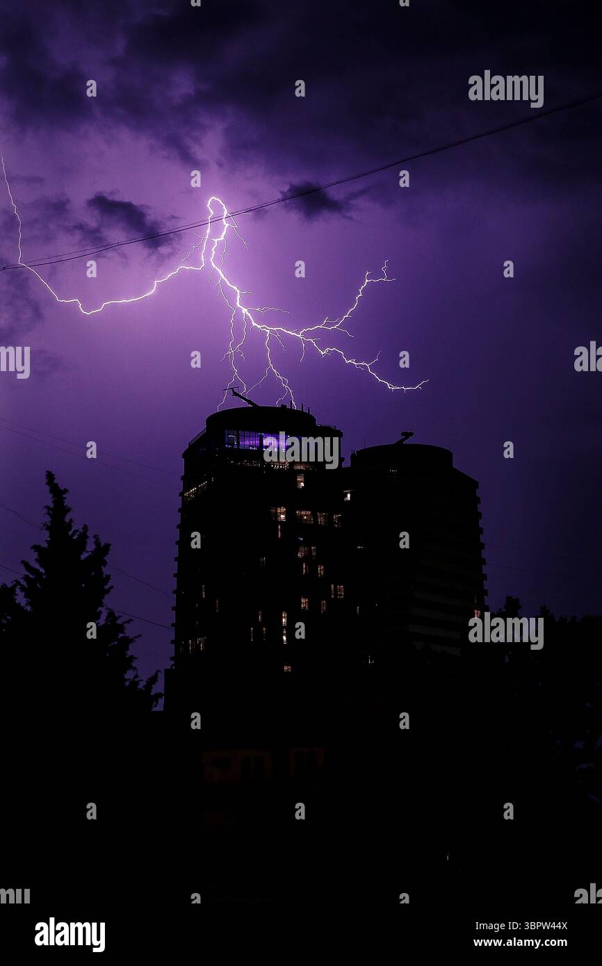 Night thunderstorm over Tbilisi’s twin towers—lightning strikes illuminate the skyline in a ...