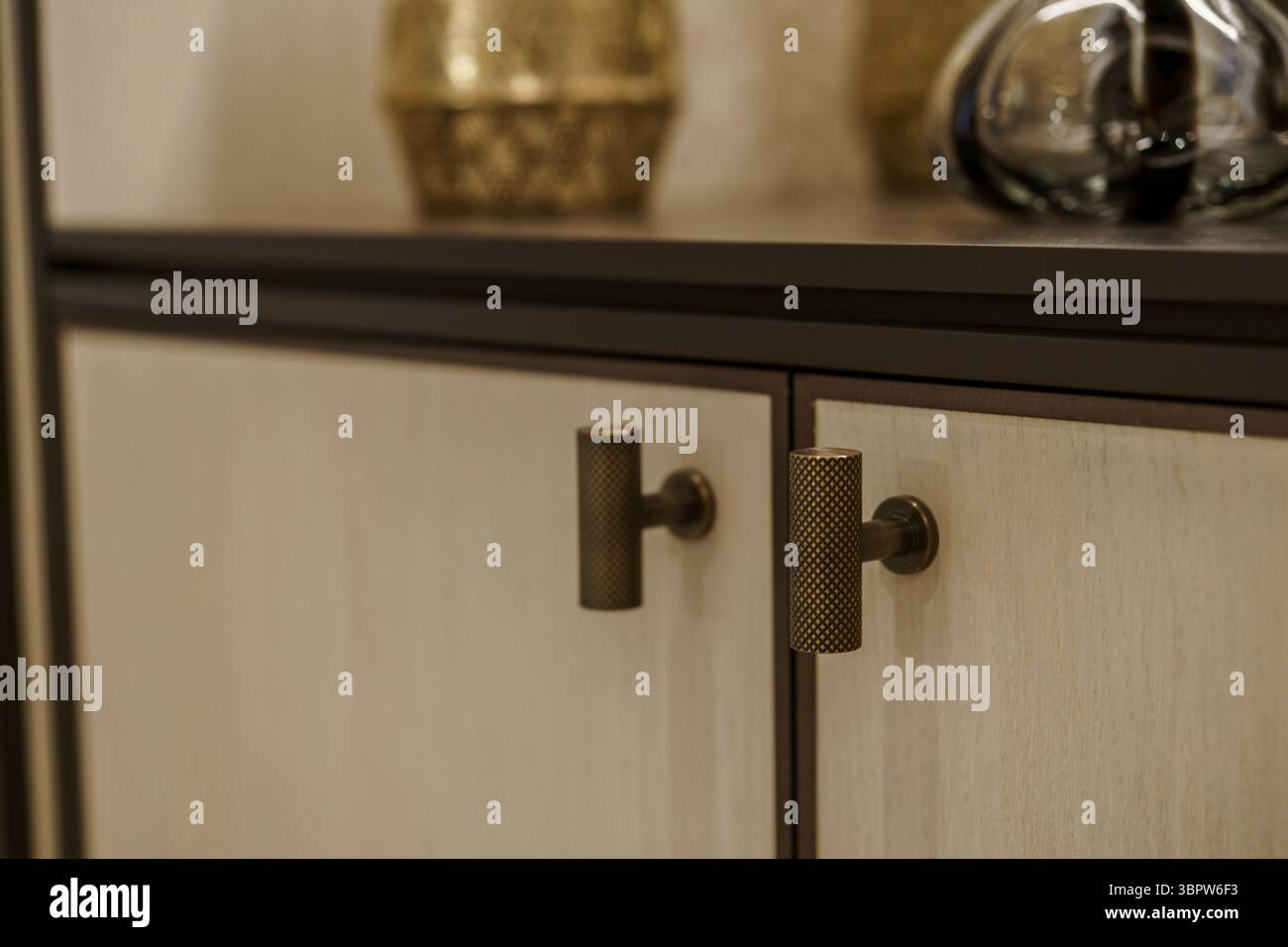 Macro detail of two modern T-bar cabinet handles with a knurled bronze ...