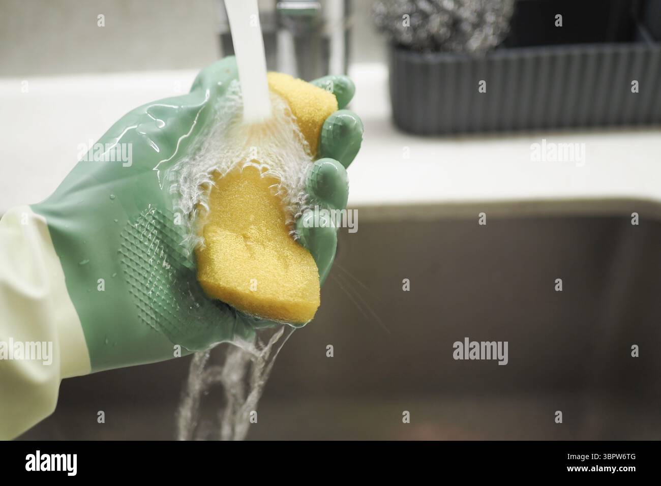Washing a sponge under running water in the kitchen sink Stock Photo ...