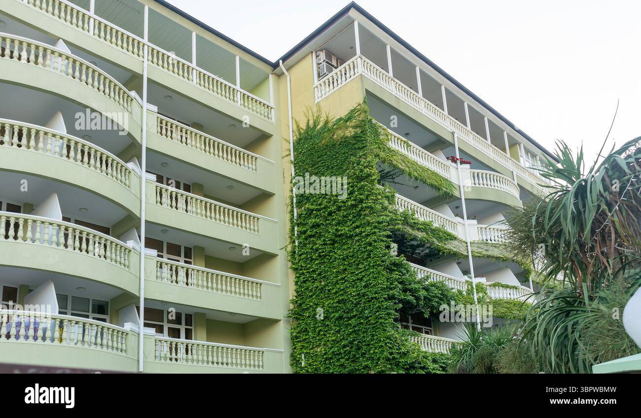 Facade of the hotel building with balconies of individual rooms. Green ...