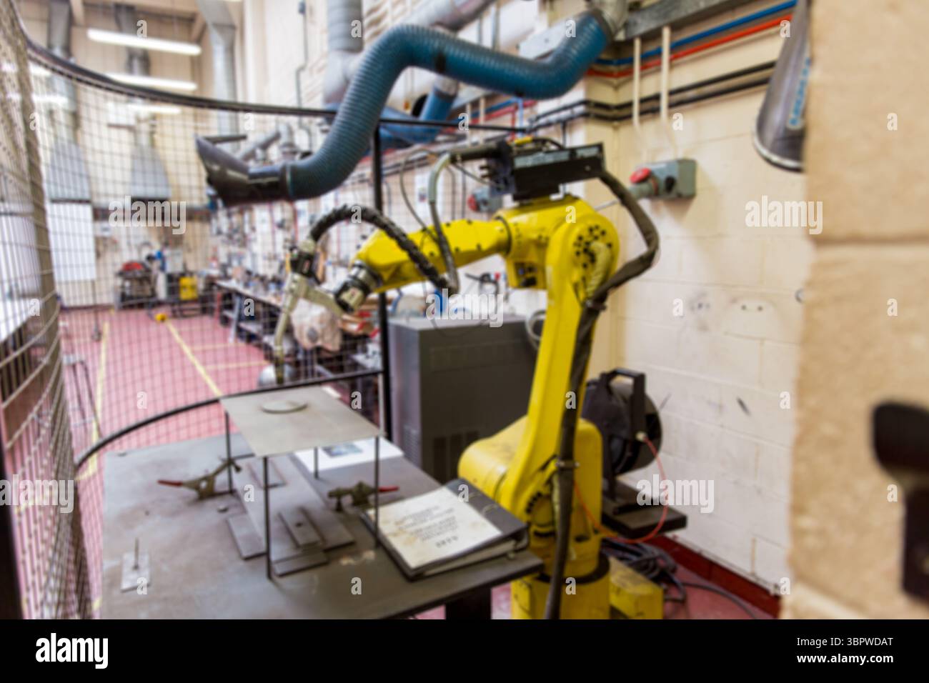Yellow industrial robotic arm is clamping metal plate inside safety ...