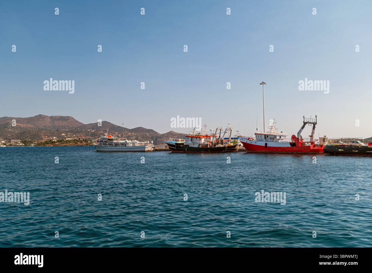 Fishing vessels rest peacefully in Agios Nikolaos harbor under clear ...