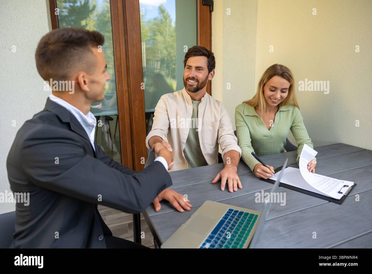 Real estate agent finalizing property contract with couple at outdoor ...