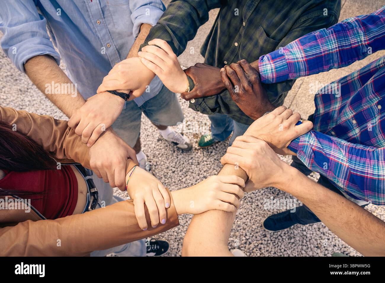 Top view of a multiethnic group of friends linking their arms in a ...