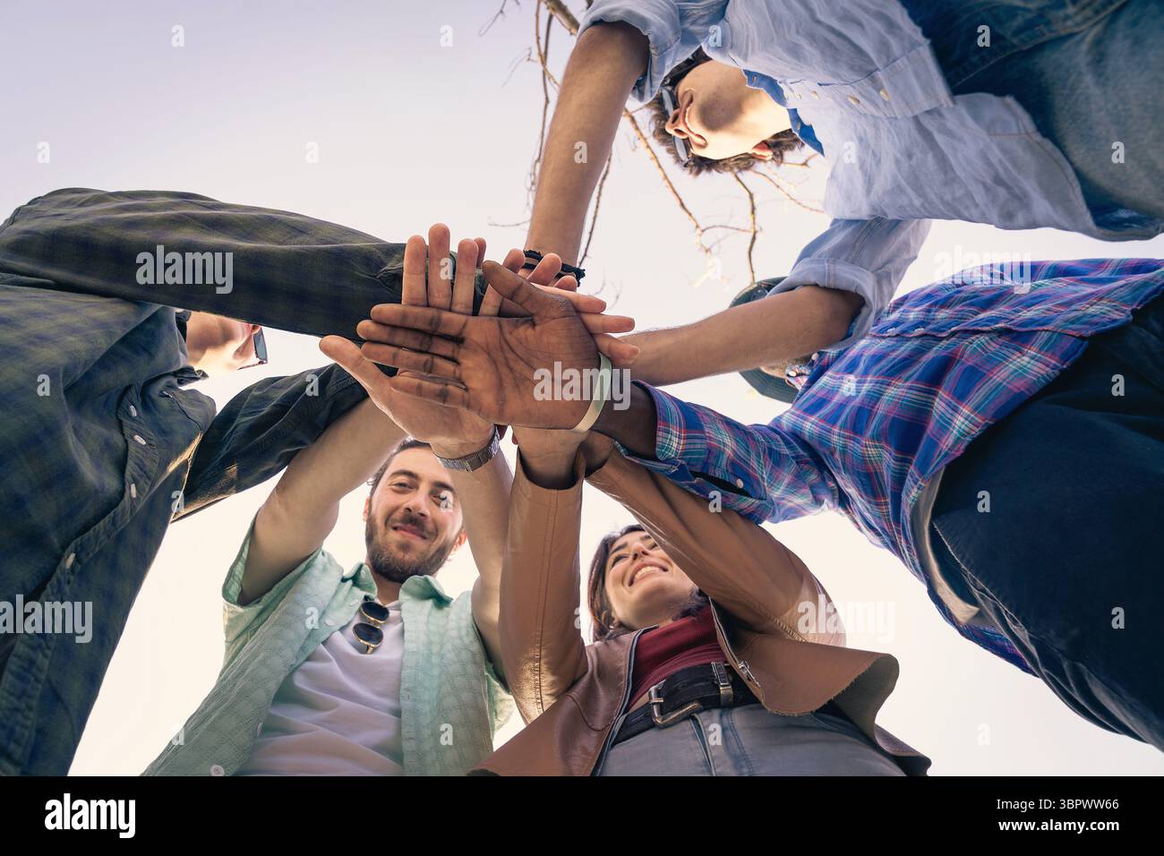 Worm's eye view of a happy diverse team putting their hands together in a huddle. Concept of ...