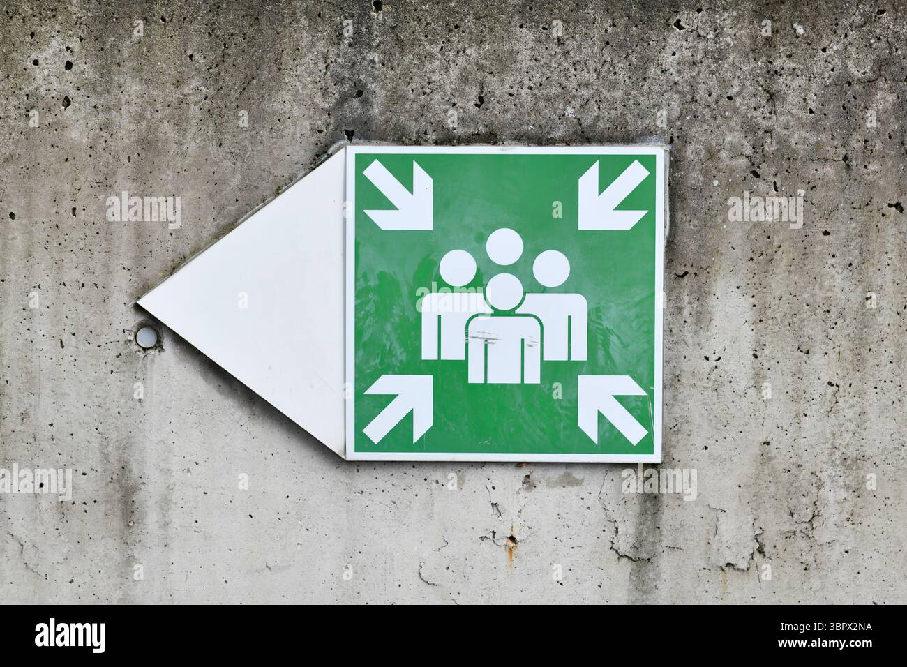 Emergency assembly point sign on concrete wall. Indicates designated ...