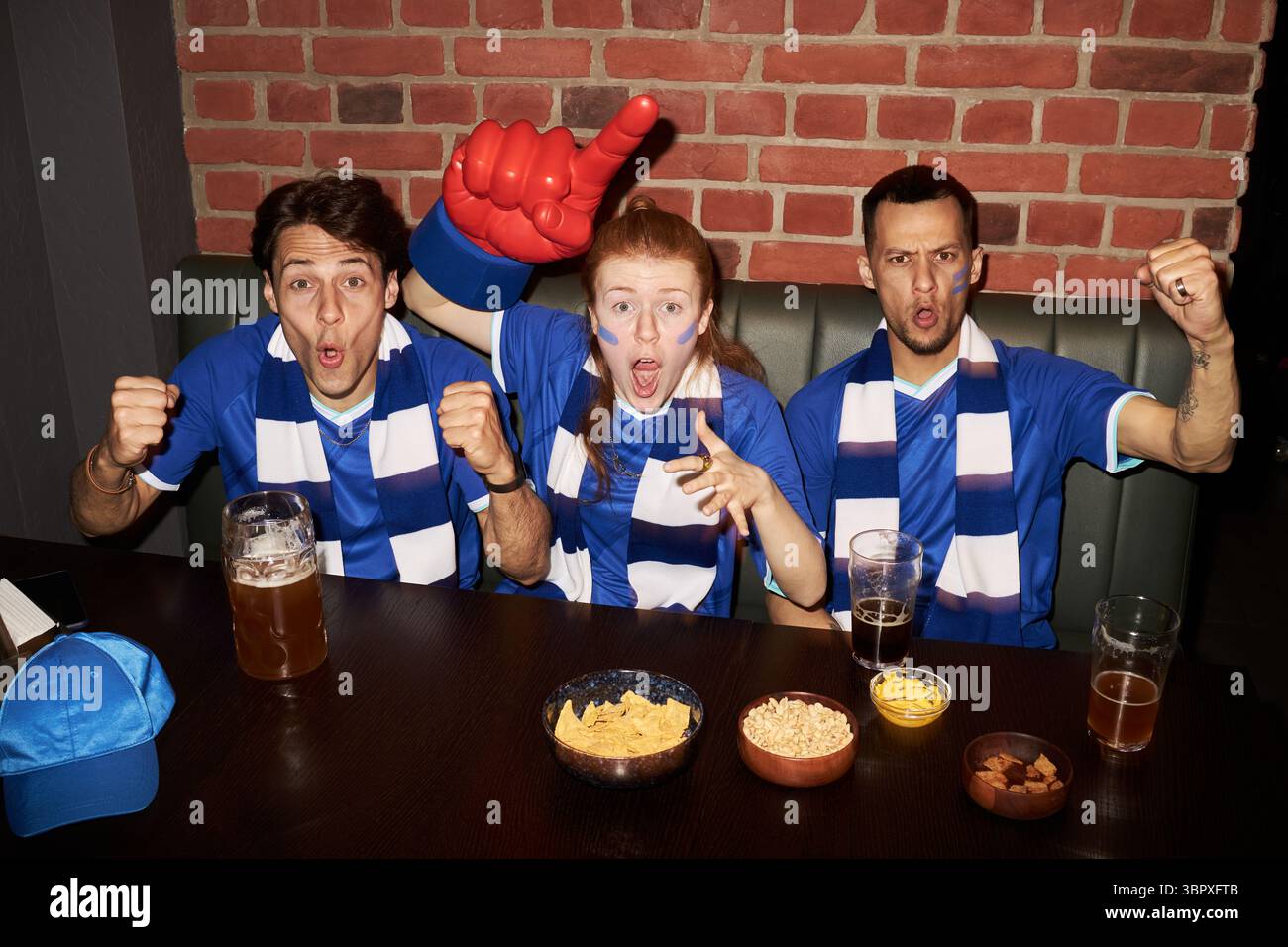 Three young Caucasian soccer fans with painted faces cheering and ...