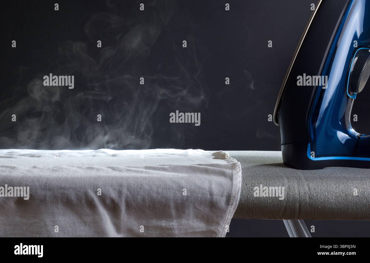 White shirt ironing, steam rising from the heat on an ironing board ...
