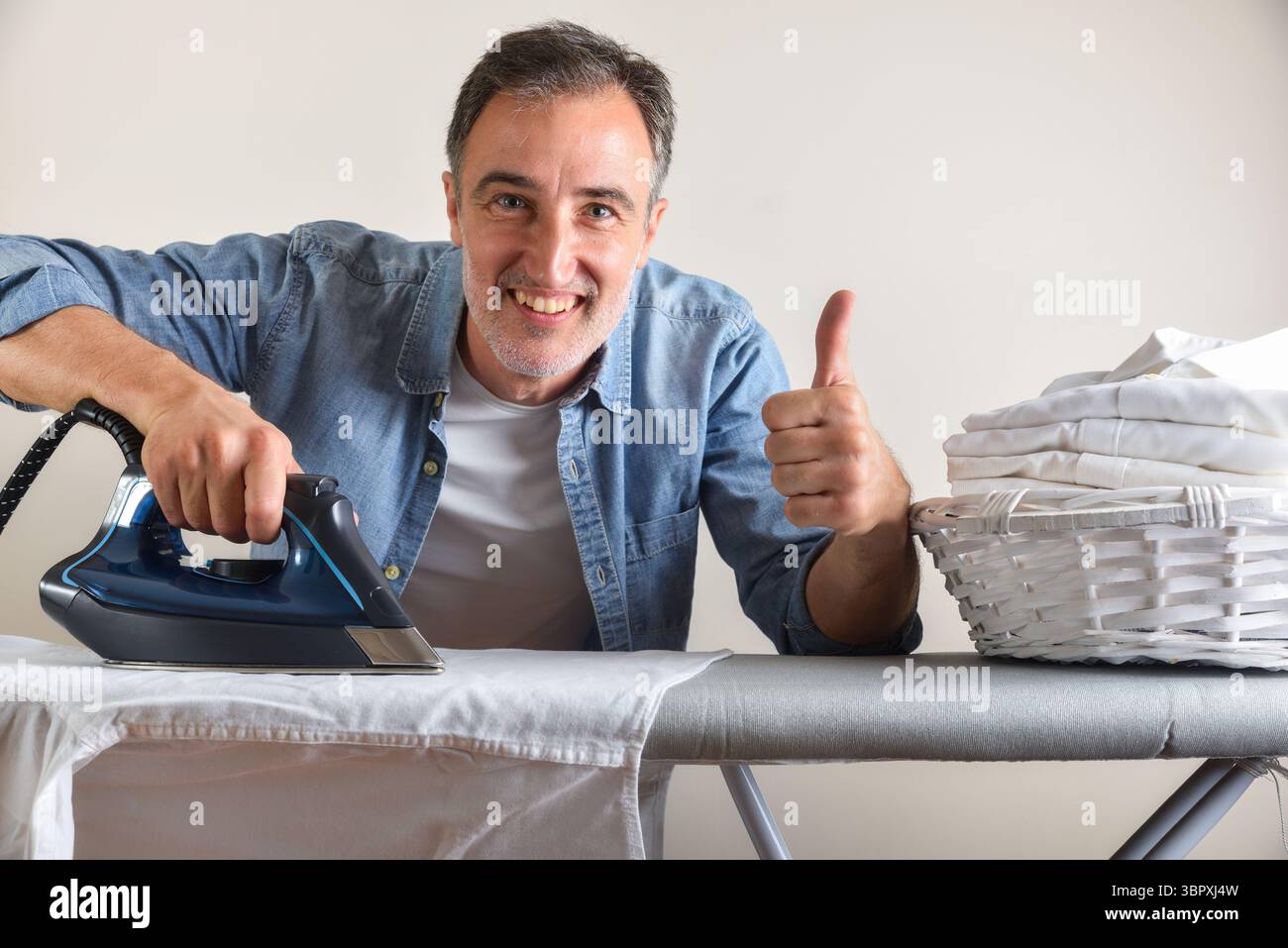 Detail of smiling elegant man ironing a white shirt on a gray ironing ...