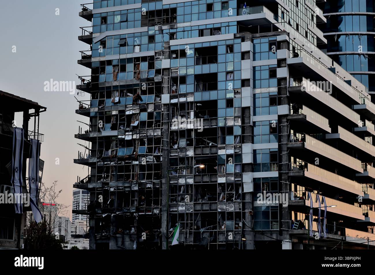 A modern high-rise in Ramat Gan stands scarred by missile fire, its ...