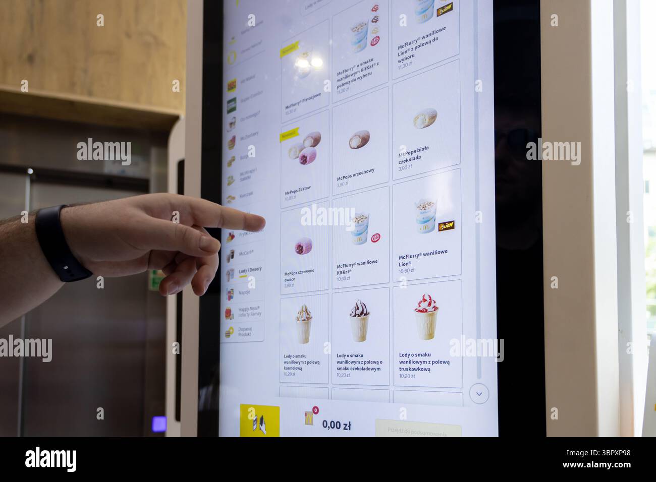 Poznan, Poland - June 18, 2025: McDonald's self-service kiosk, a customer's hand selecting menu ...