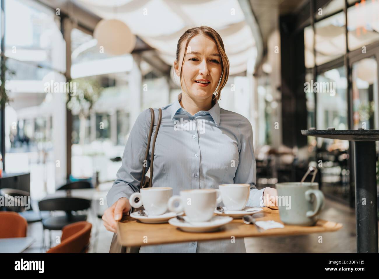 Professional waitress serving coffee on a tray in a bustling outdoor cafe setting Stock Photo ...