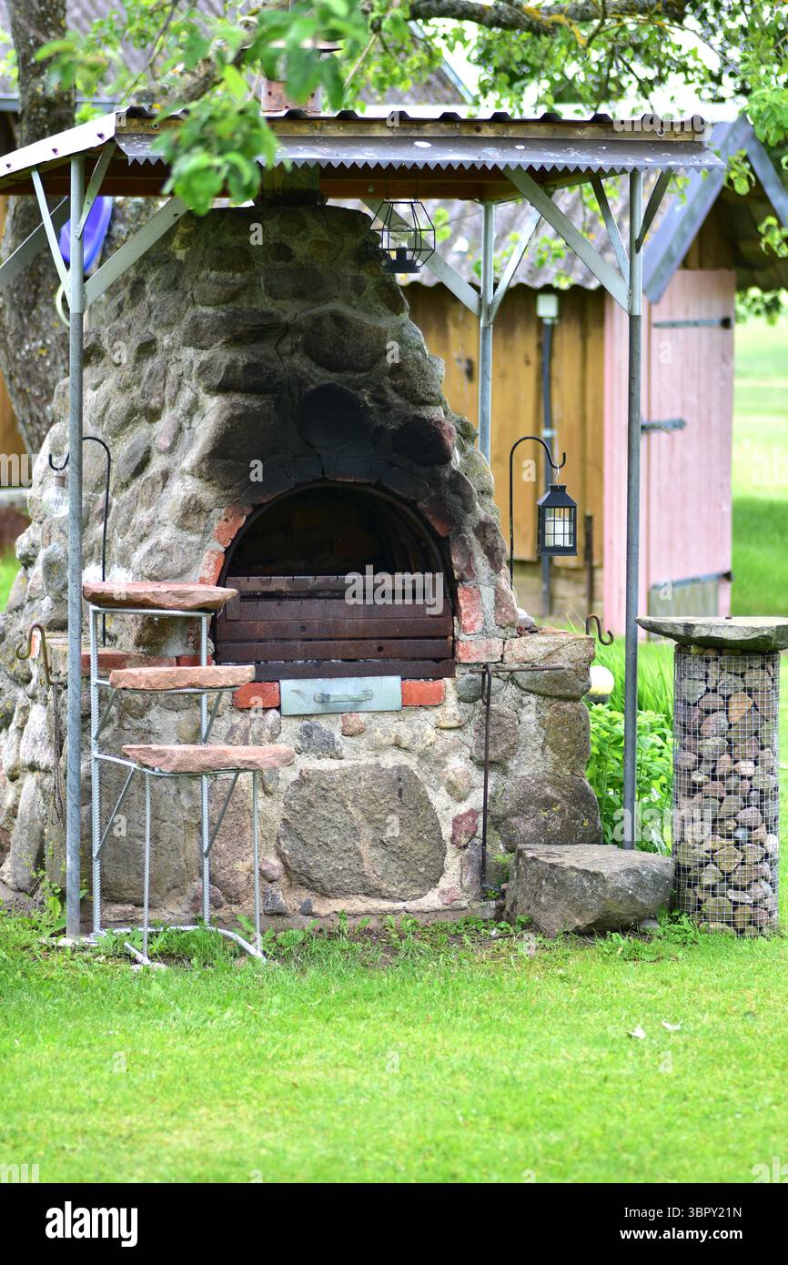 Rustic stone oven with metal roof in countryside backyard in summer ...