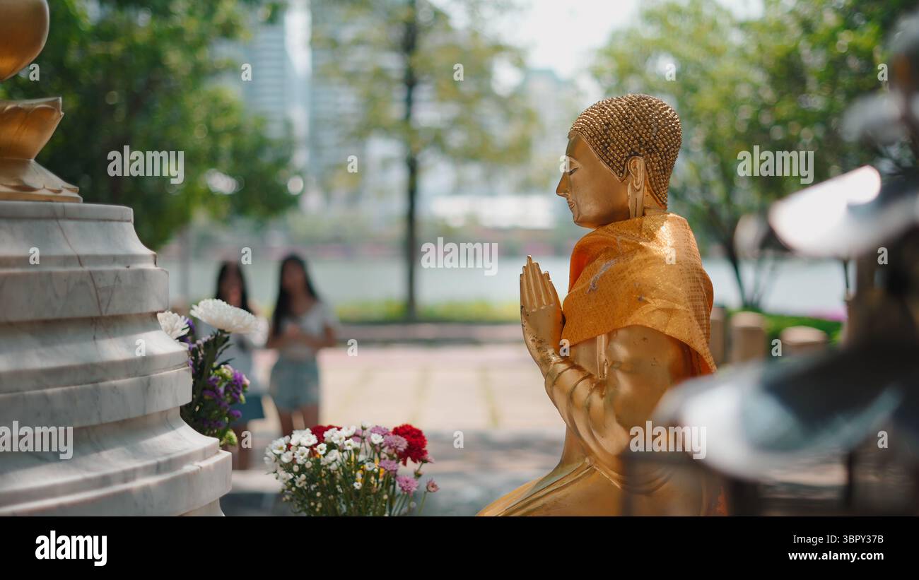 Golden buddha statue with flowers in a peaceful outdoor setting Stock ...