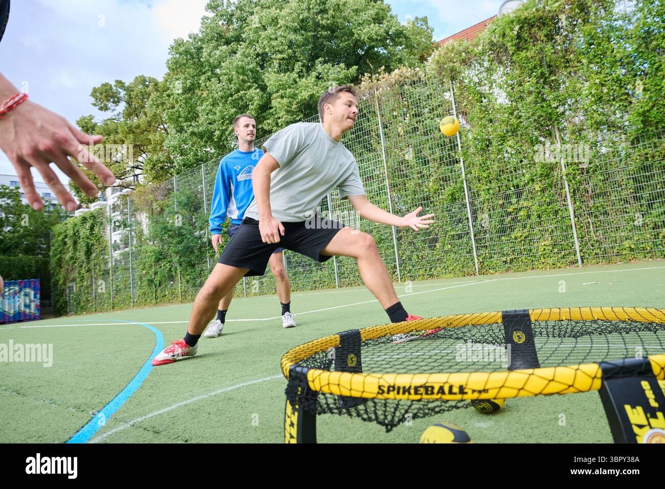 PRODUCTION - 09 July 2025, Berlin: Till (center) and Jan (r) play Roundnet on a sports field in ...