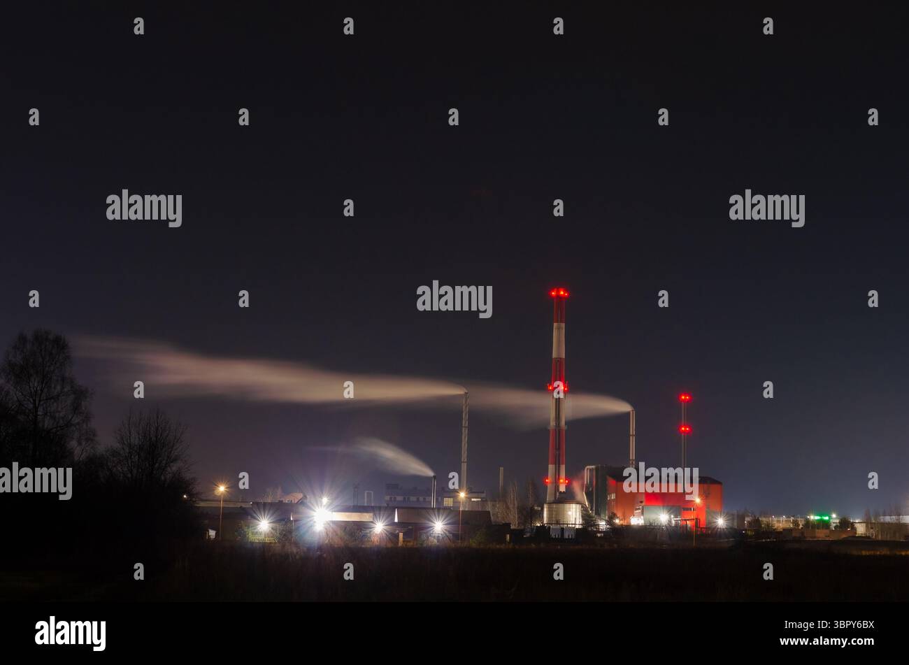Iindustrial factory emitting smoke into the dark night sky with glowing ...