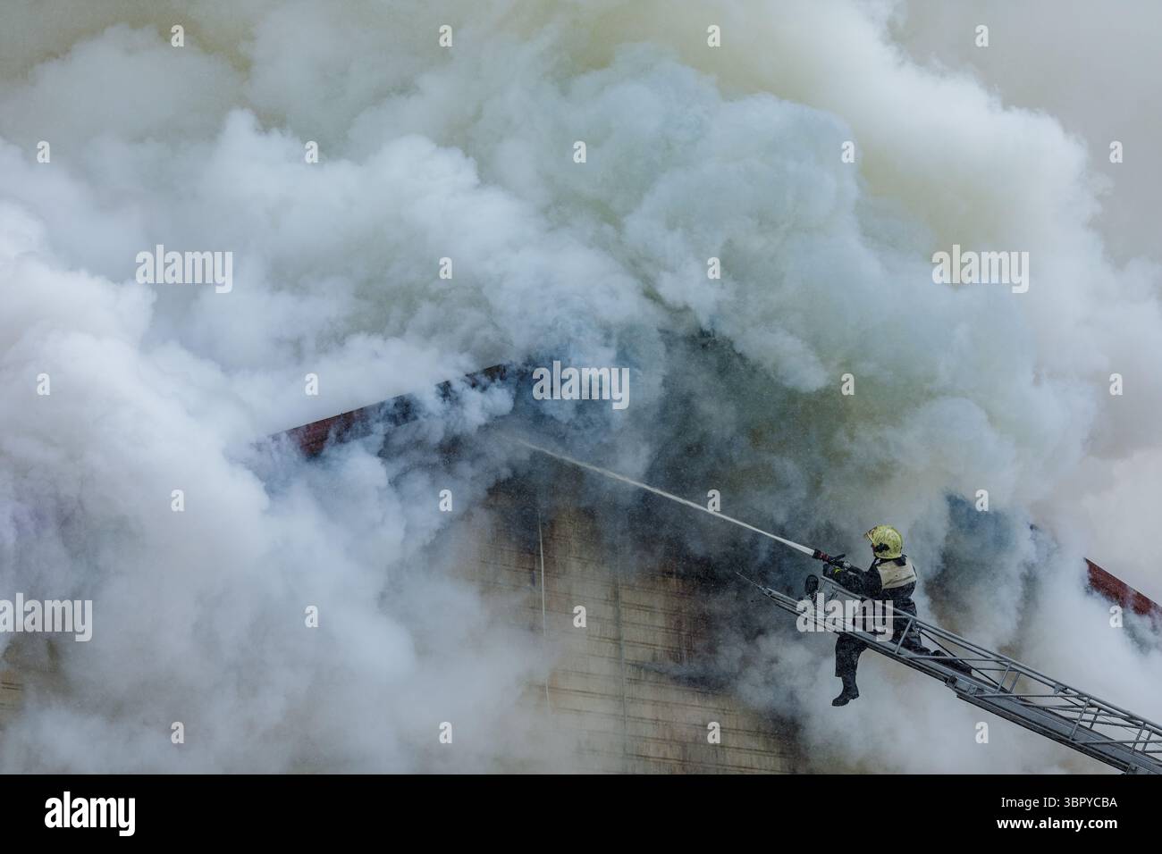 Firefighter in gear battles roof fire with dense smoke, showcasing ...