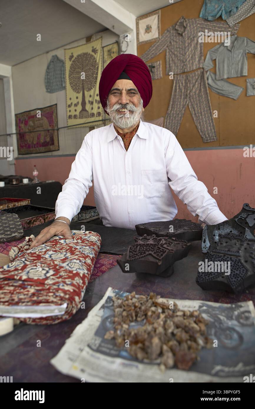 Indian Sikh, 68 years old, in his shop, in front bales of cloth and ...